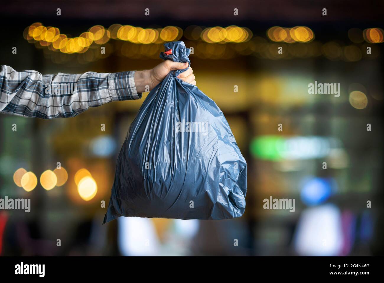 hand holding the dark blue trash bag, concept of cleaning earth planet ...