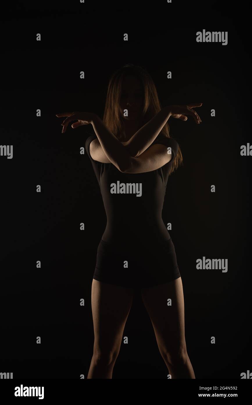 Female silhouette is posing with her arms while holding the posture ...