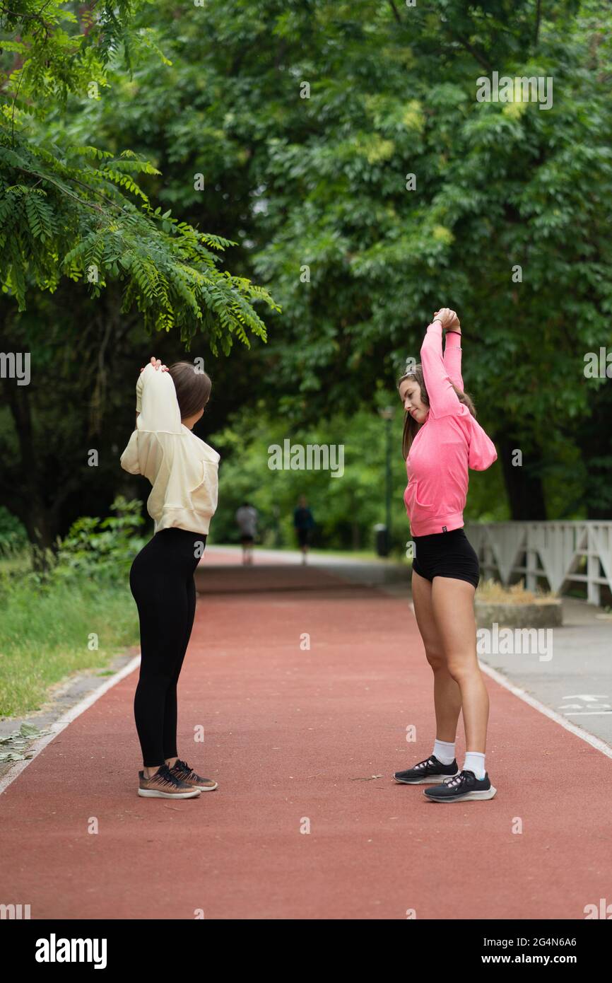 Two attractive girls are stretching their hand together before the ...