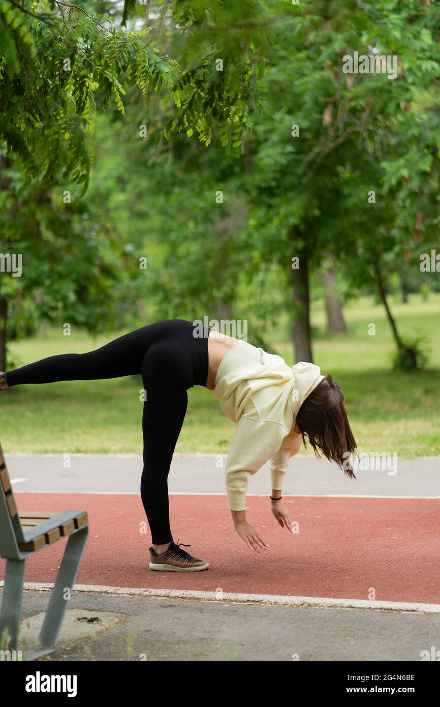 Attractive and beautiful young girl is trying to stretch her leg up ...