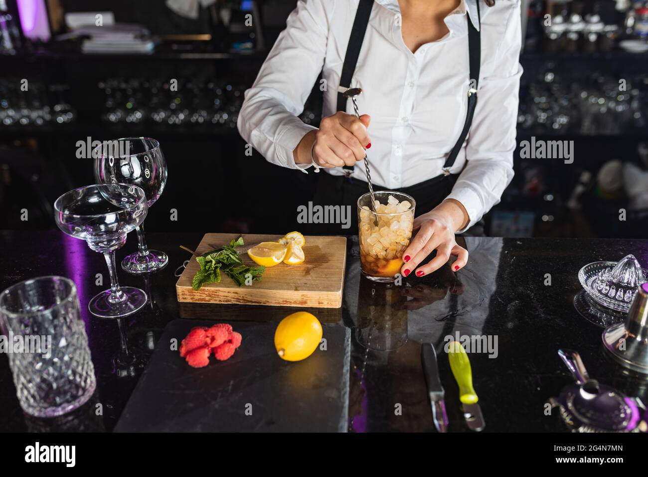 Cropped unrecognizable female barkeeper in stylish outfit adding ice ...