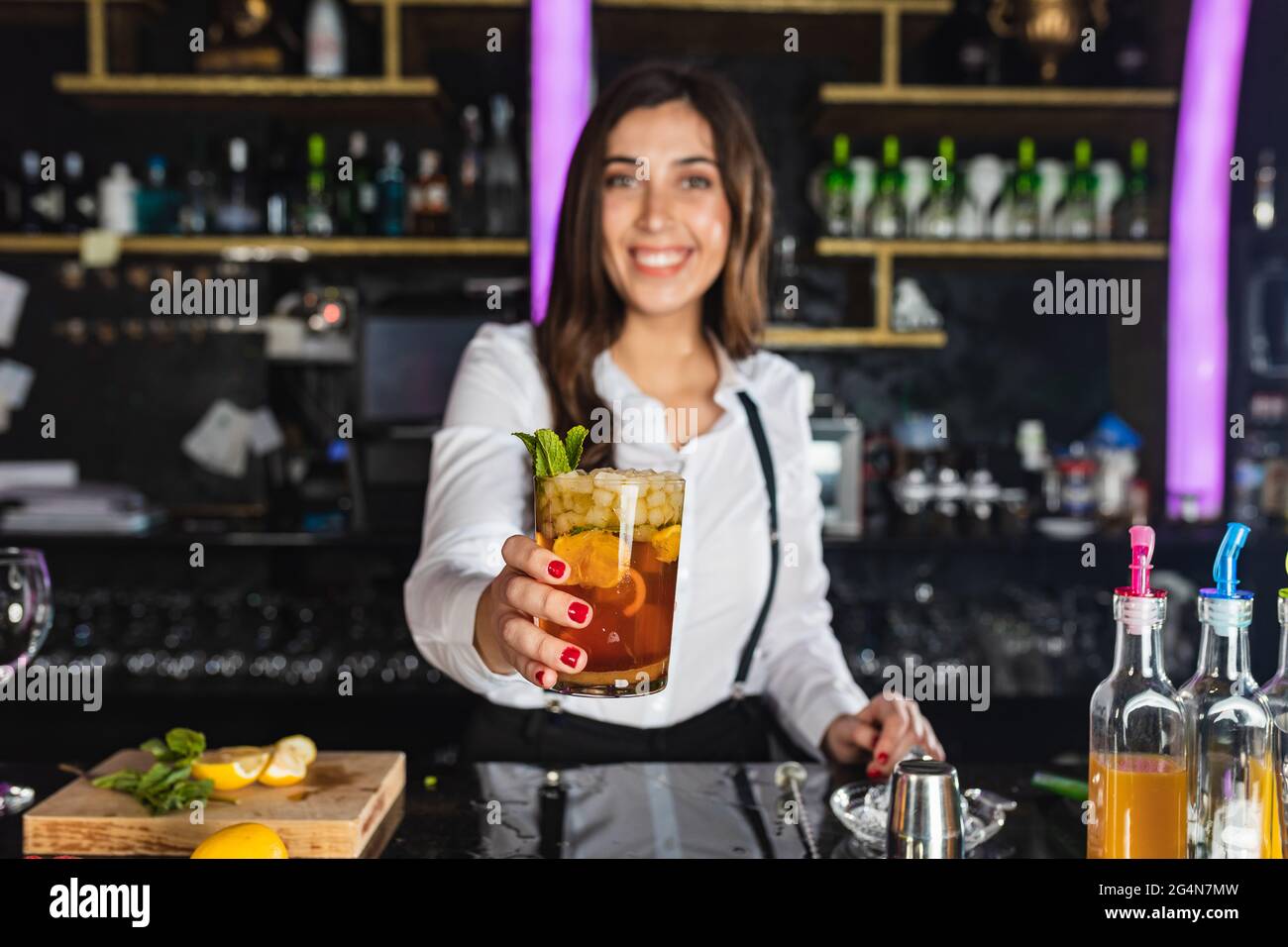 Happy young female barkeeper in stylish outfit looking at camera ...