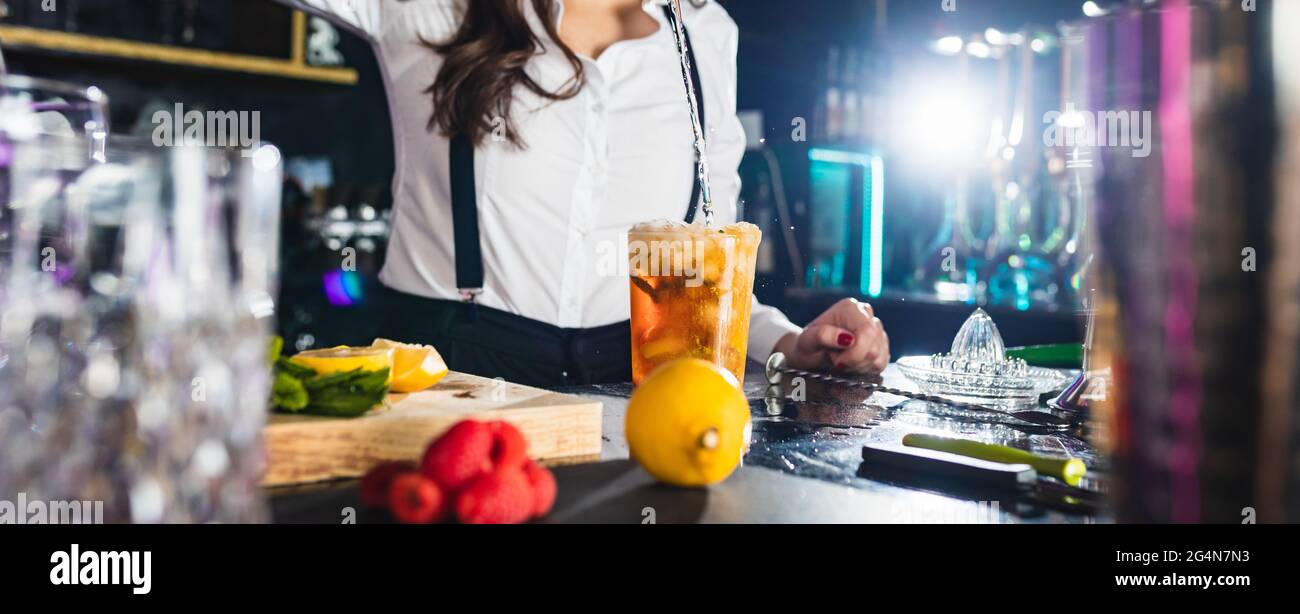 Cropped unrecognizable female barkeeper in stylish outfit liquid from ...