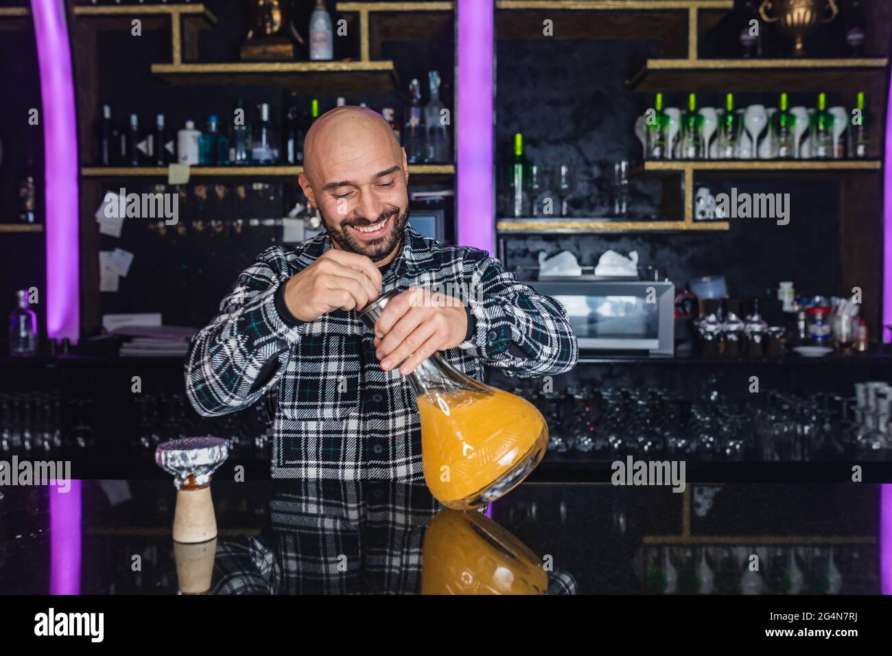 happy man preparing a big glass traditional hookah in a night club ...
