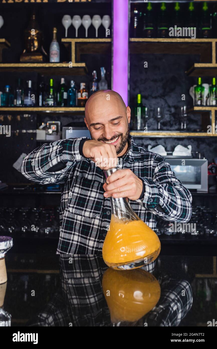 happy man preparing a big glass traditional hookah in a night club ...