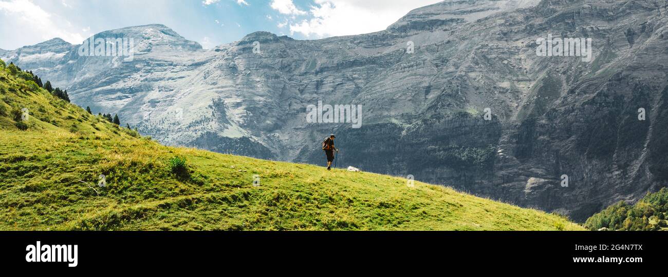 Panoramic side view of unrecognizable men hiking green mountain in the ...