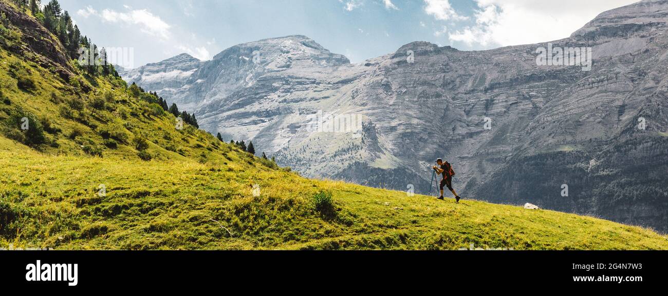 Panoramic side view of unrecognizable men hiking green mountain in the ...