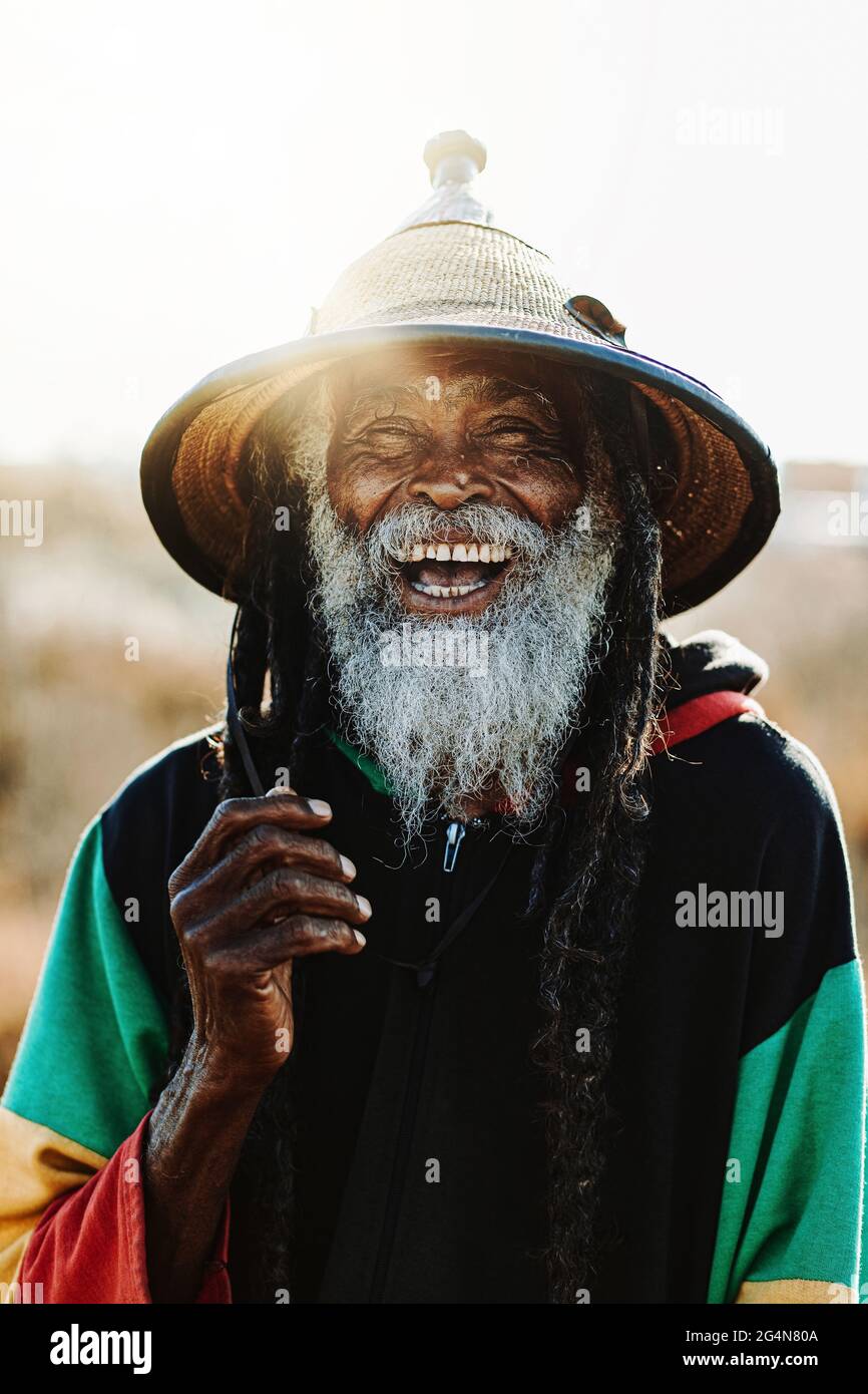 Portrait of cheerful old ethnic rastafari with dreadlocks looking at ...