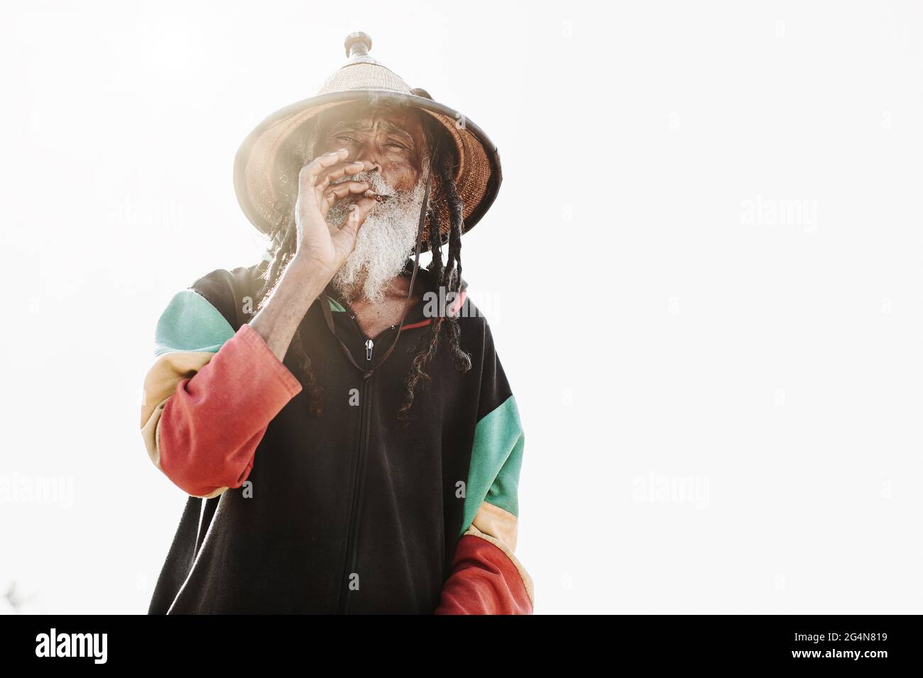 Cheerful old ethnic rastafari with dreadlocks looking at the camera ...