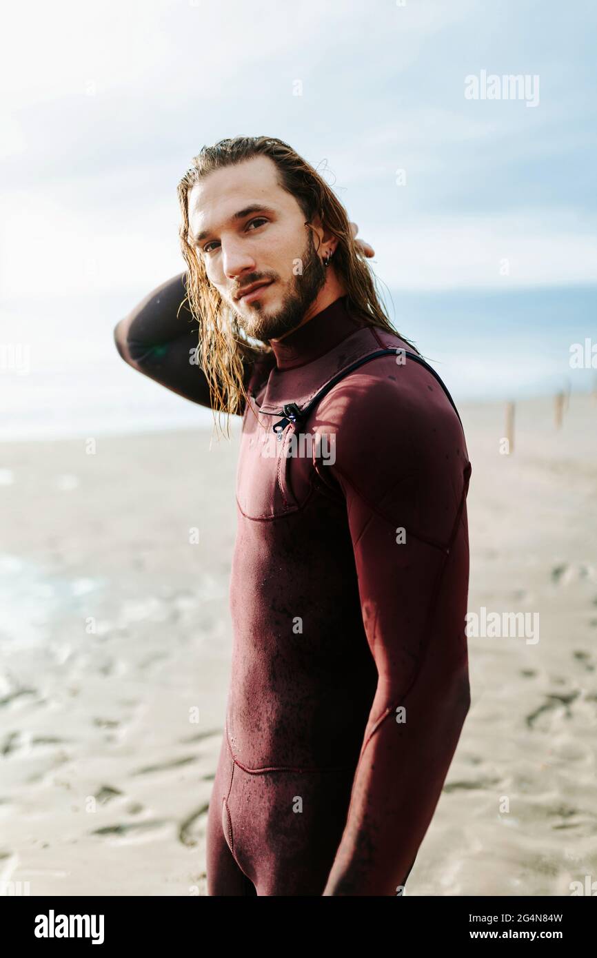 Side view of young handsome surfer man with long hair dressed in ...