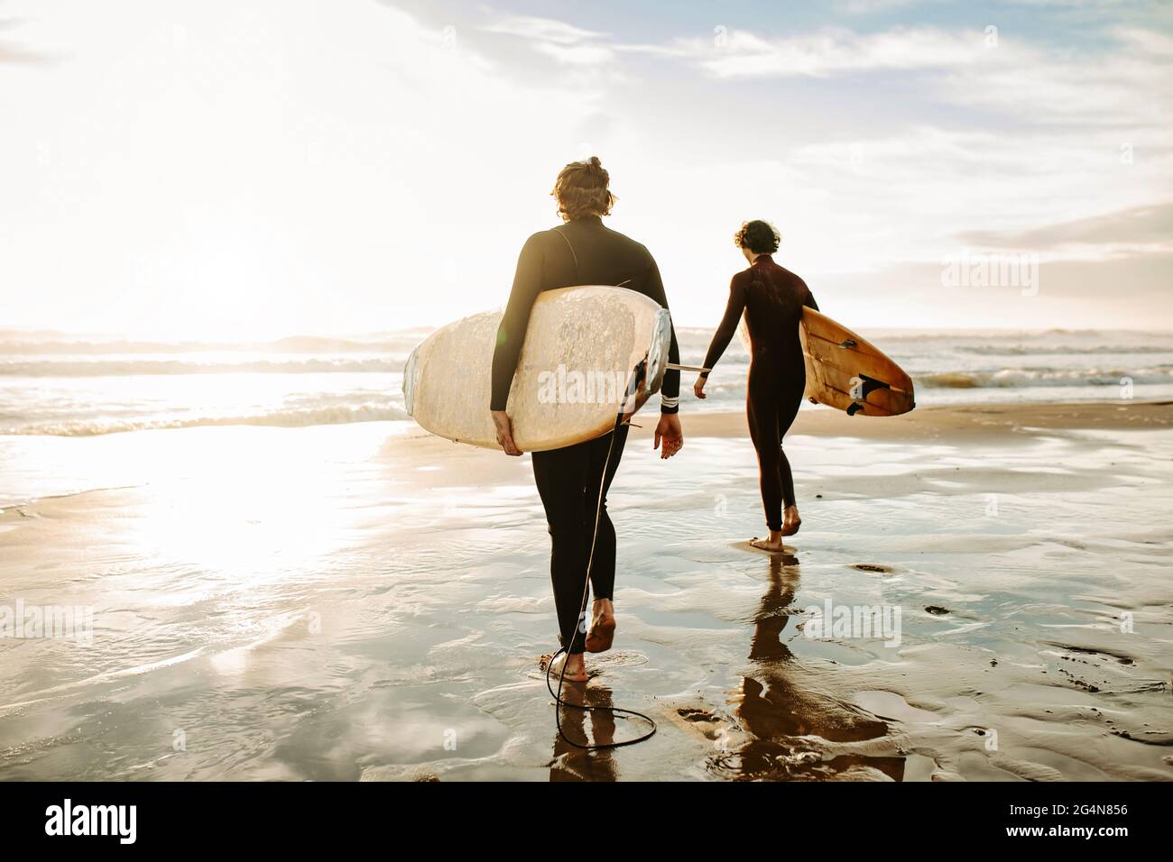 Back view of unrecognizable male surfer friends dressed in wetsuits ...