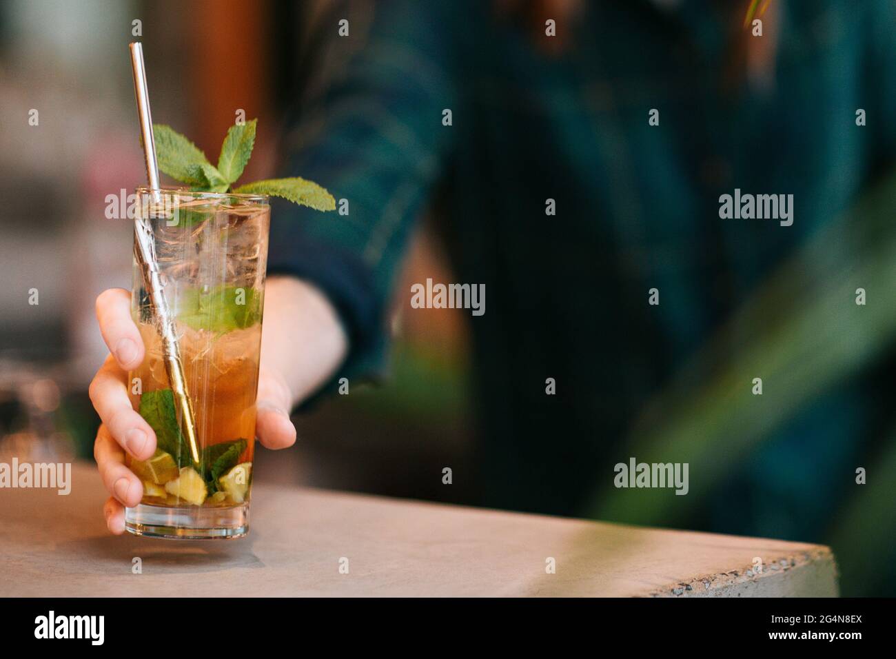 Crop anonymous bartender with glass of Mojito consisting of white rum ...