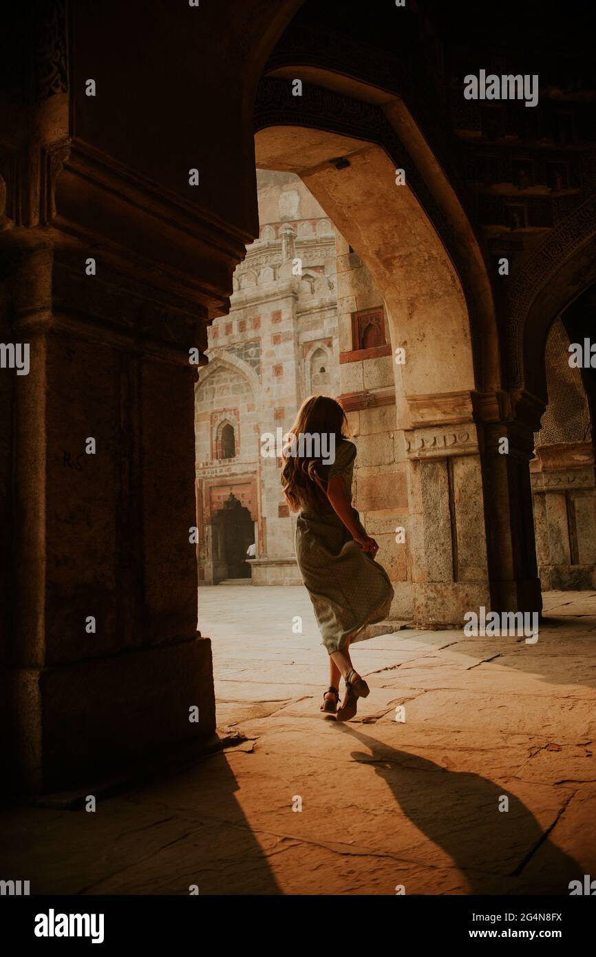 Full body back view of anonymous female tourist running under arched ...