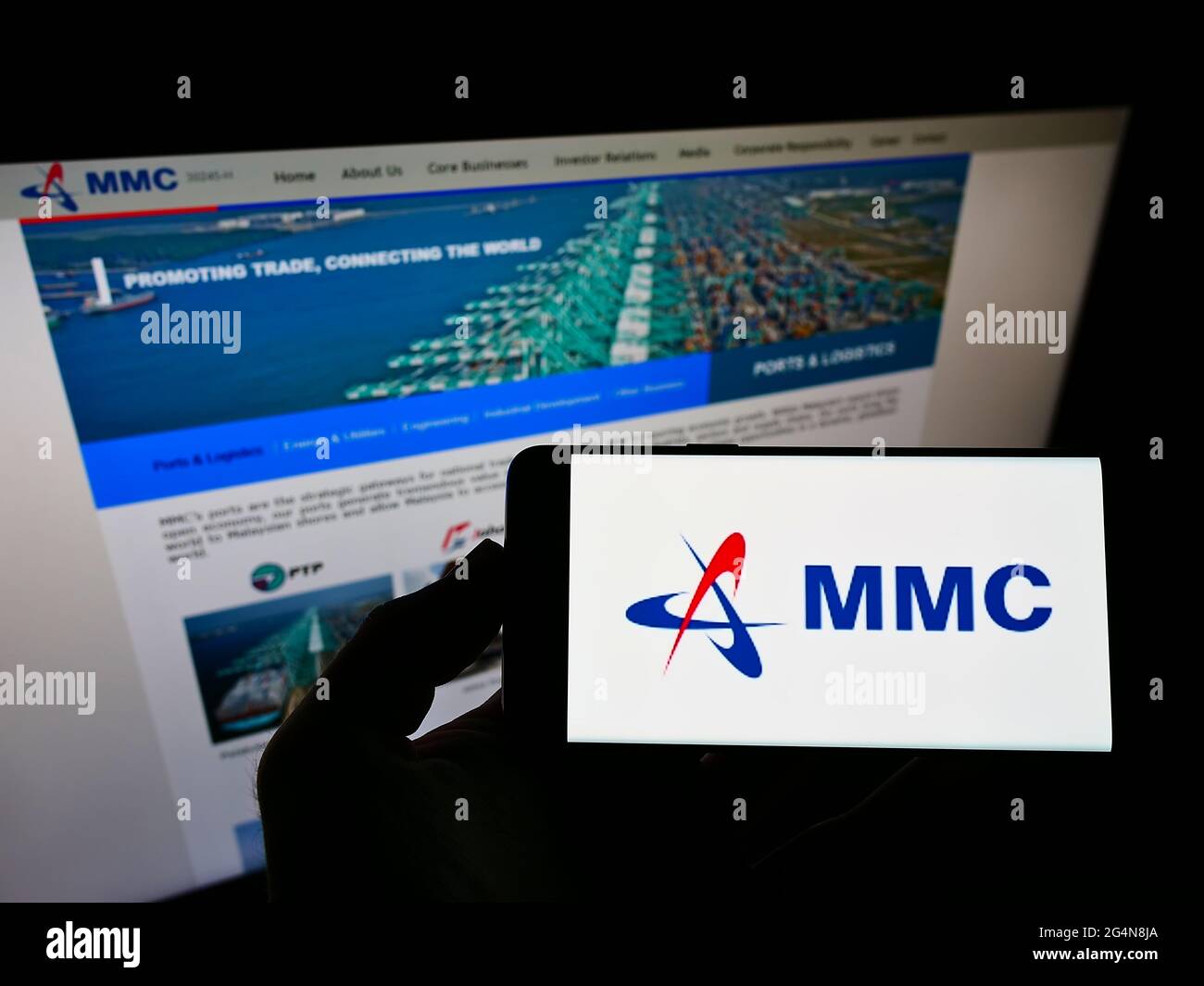 Person holding mobile phone with logo of Malaysian company MMC ...