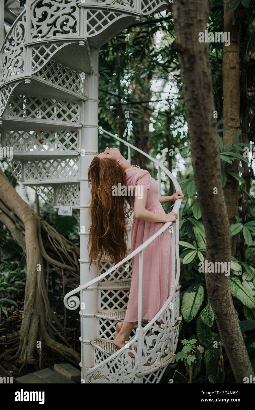 Side view full body of female with long hair standing near railing of ...