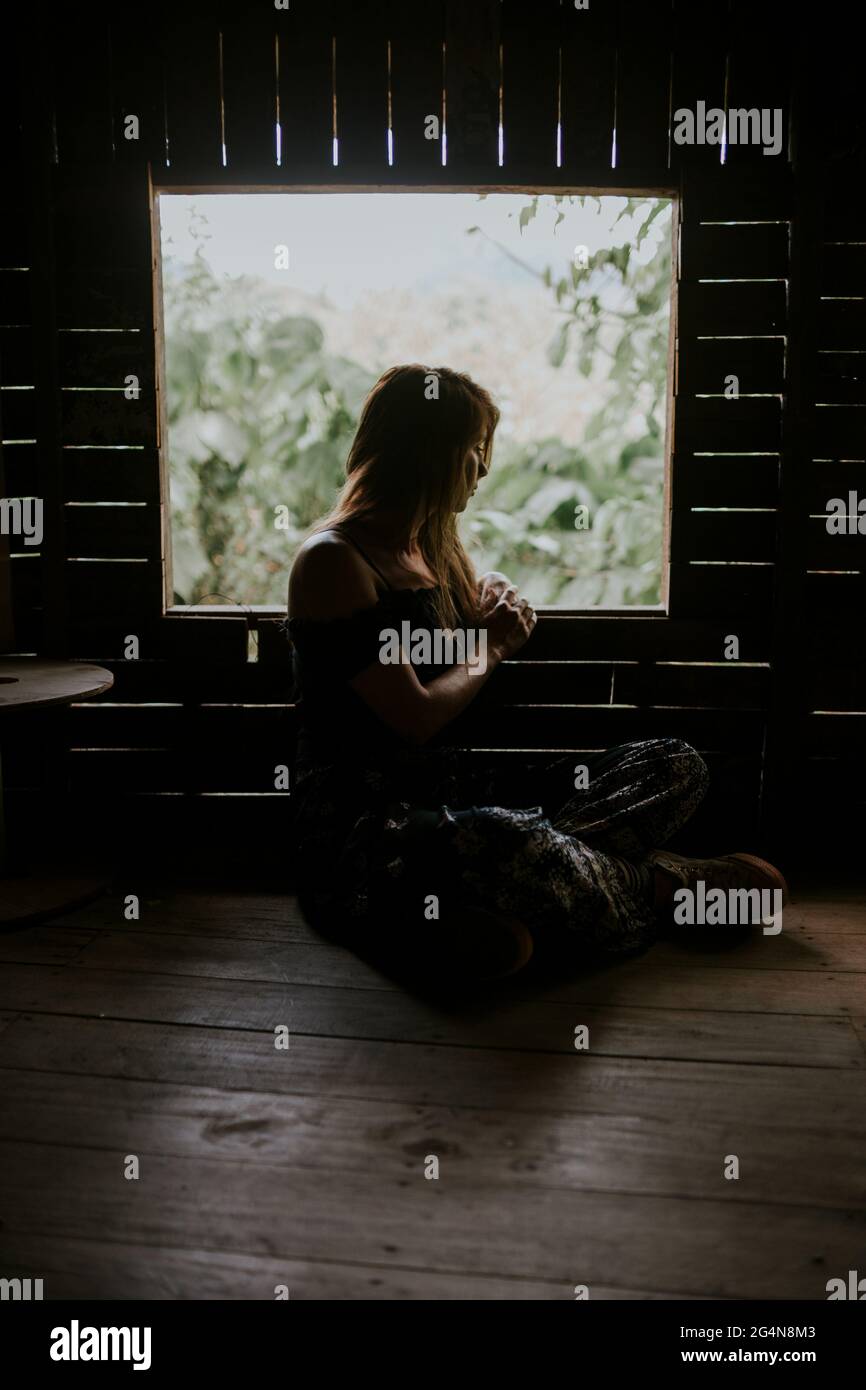 Full body side view of tranquil female sitting in wooden cabin near ...