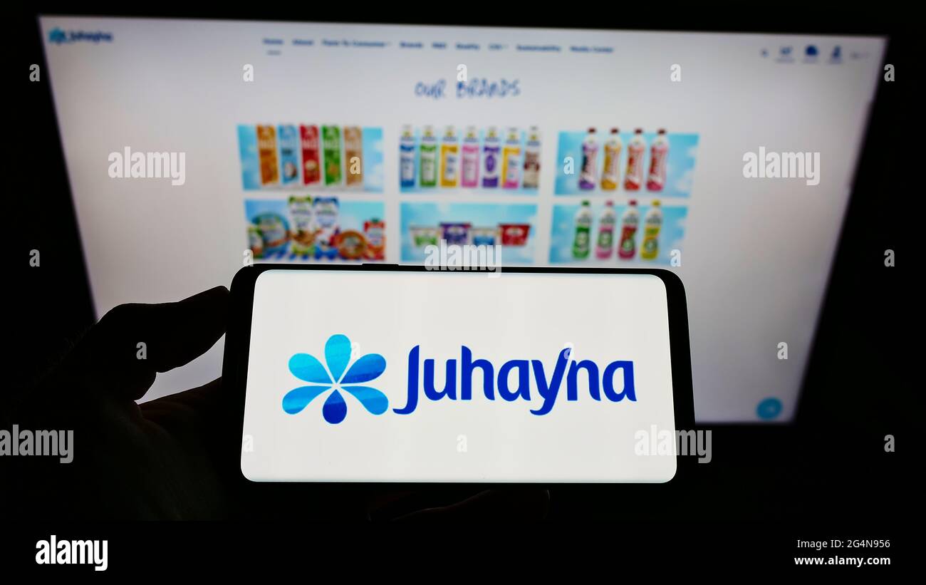 Person holding smartphone with logo of Egyptian company Juhayna Food ...