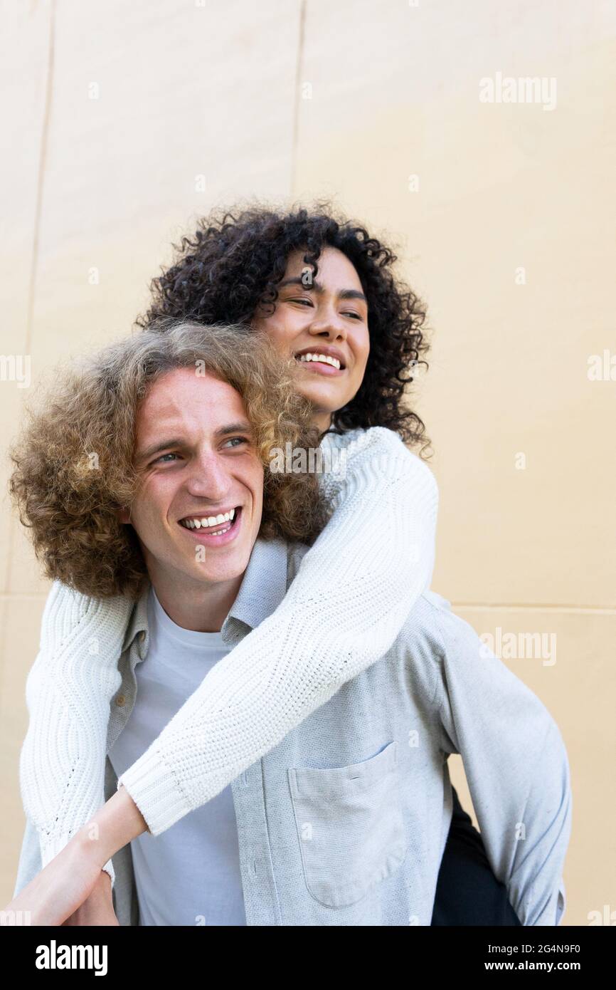 Cheerful man giving piggyback ride to diverse female friend both with ...