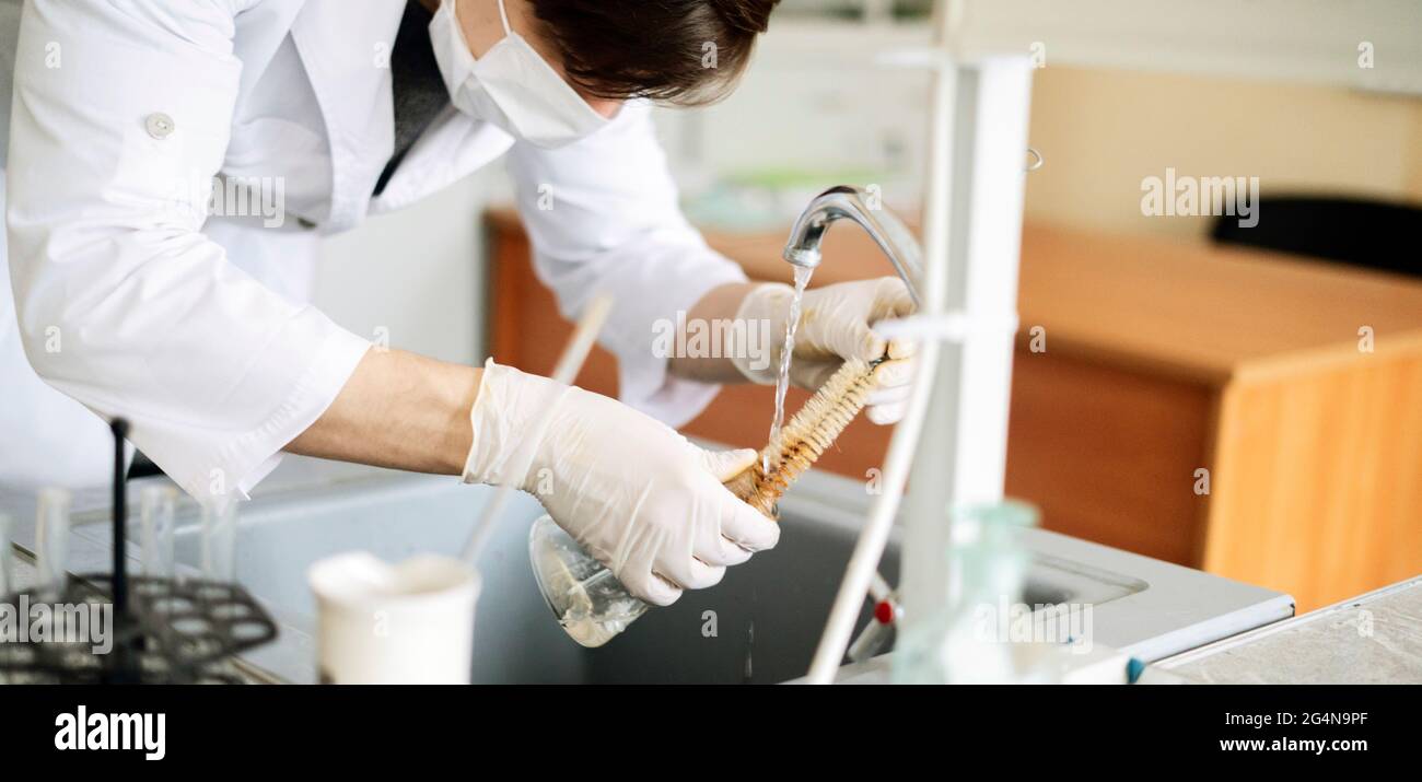 person hands in gloves cleaning and washing glass flasks with water in ...