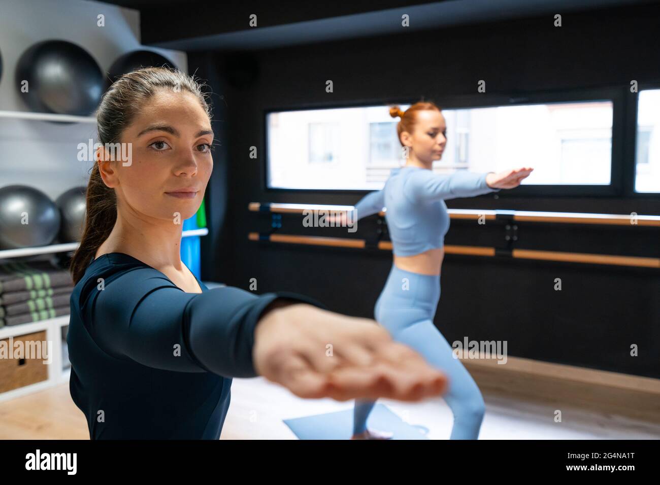 Focused young female instructor standing in Warrior II position while ...