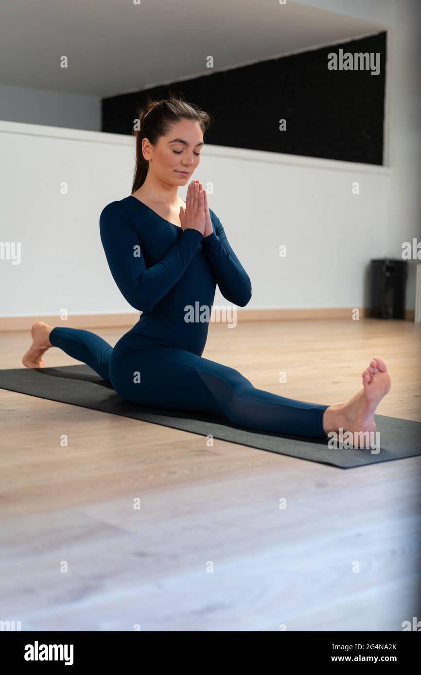 Full body of focused young female in activewear doing Front Splits pose ...