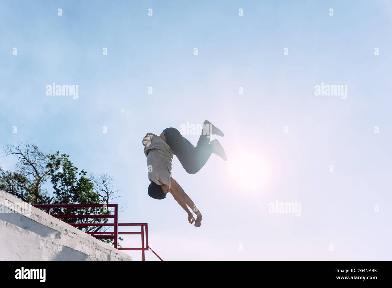 Low angle fearless young man jumping above metal railing in city while ...