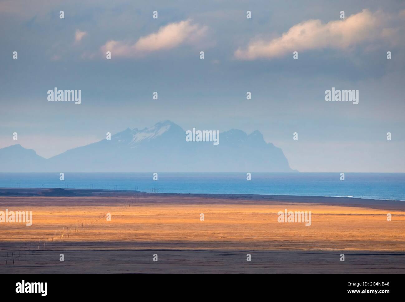 Plain dry shore and calm blue sea located against distant mountain ...