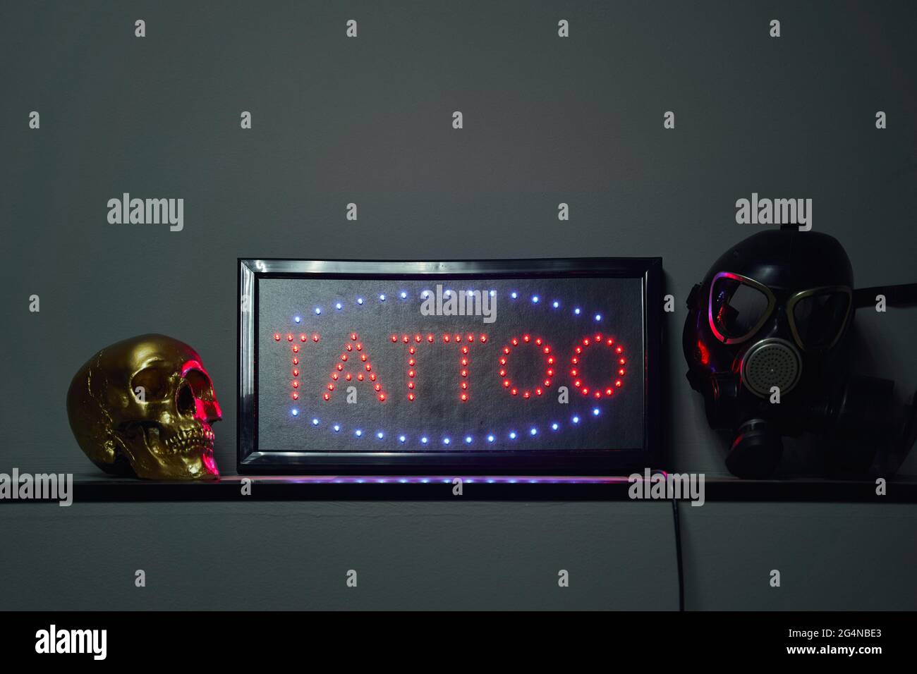 Glowing signboard with red word tattoo around blue neon lights on shelf ...