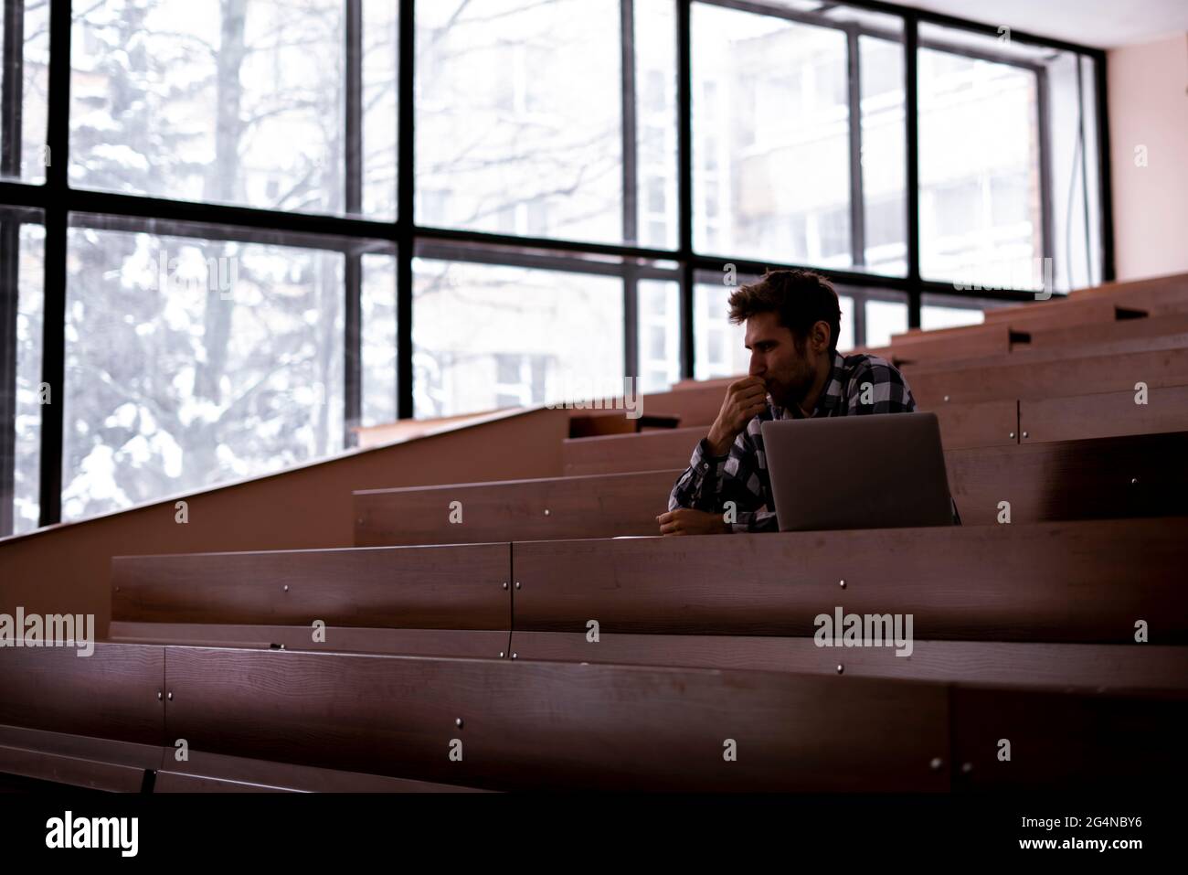alone young student sitting in the lecture hall listentng to the ...