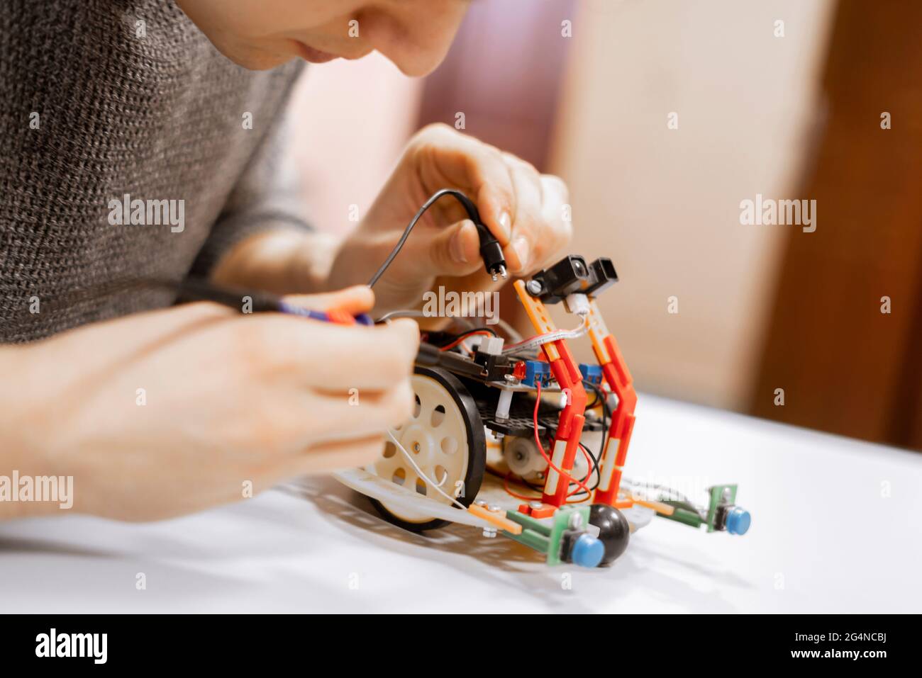 young male constructor scientist assemble the wheeled machine robot in ...