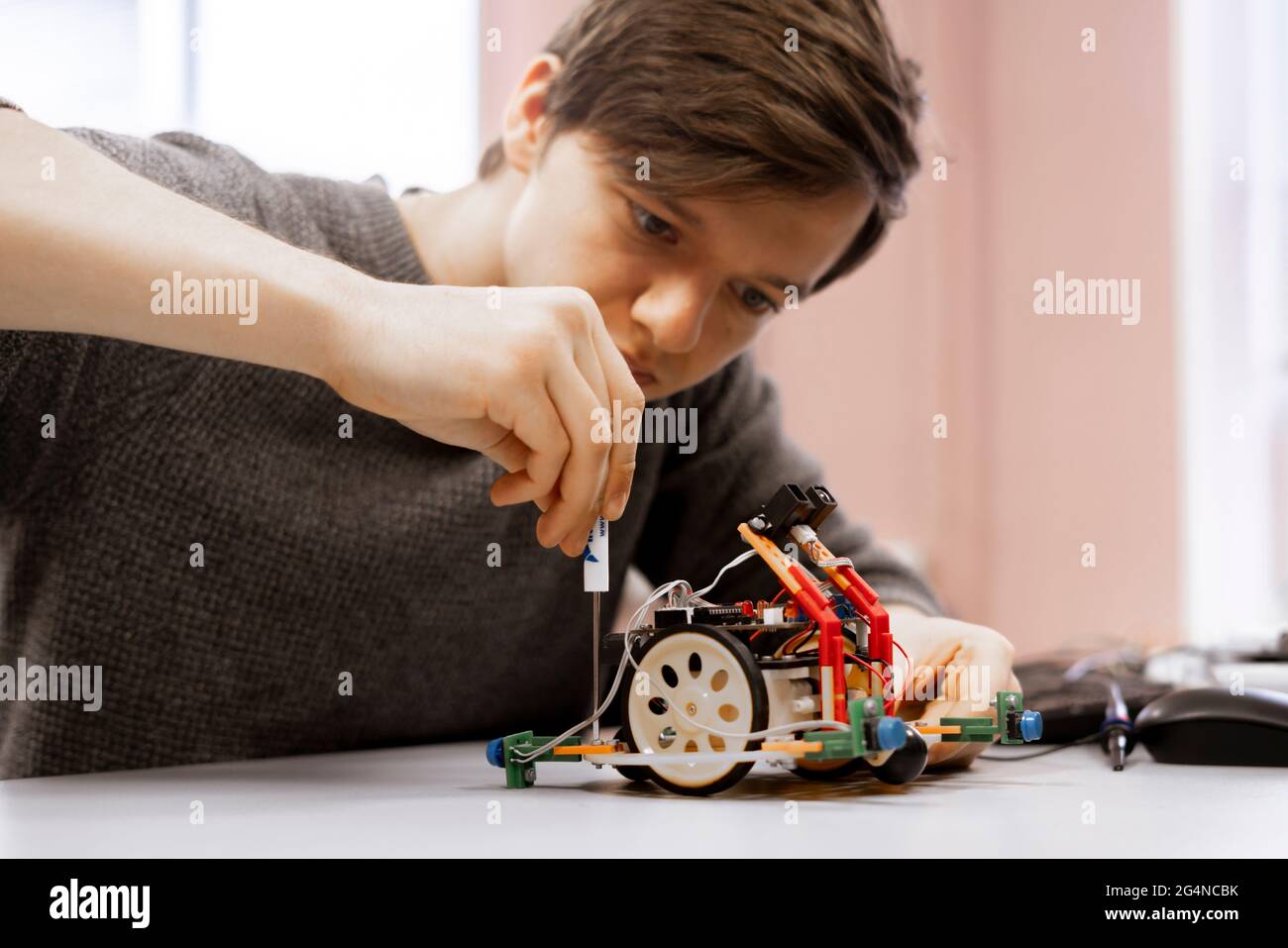 young male constructor scientist assemble the wheeled machine robot in ...