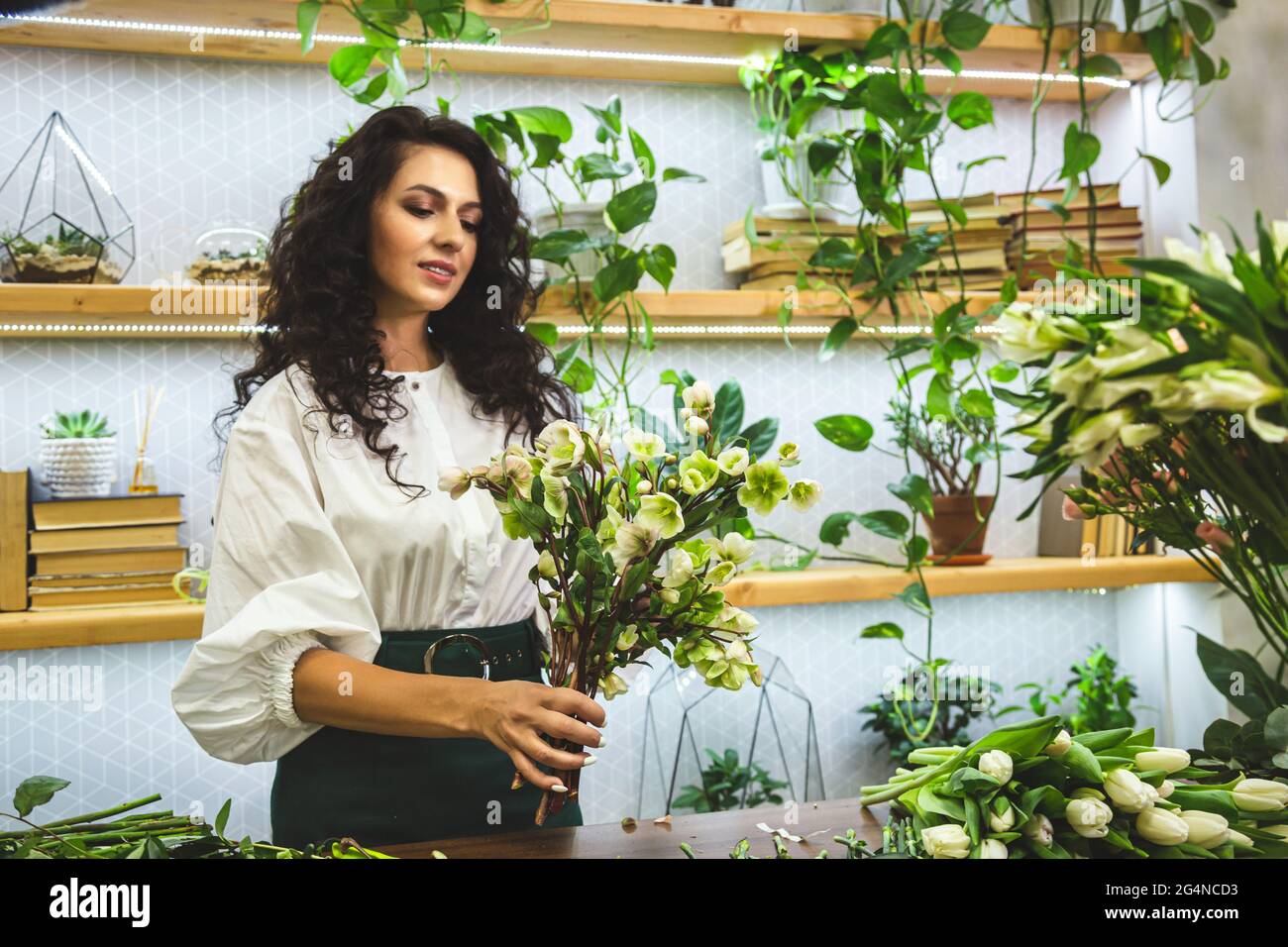 Attractive young woman florist is working in a flower shop Stock Photo ...