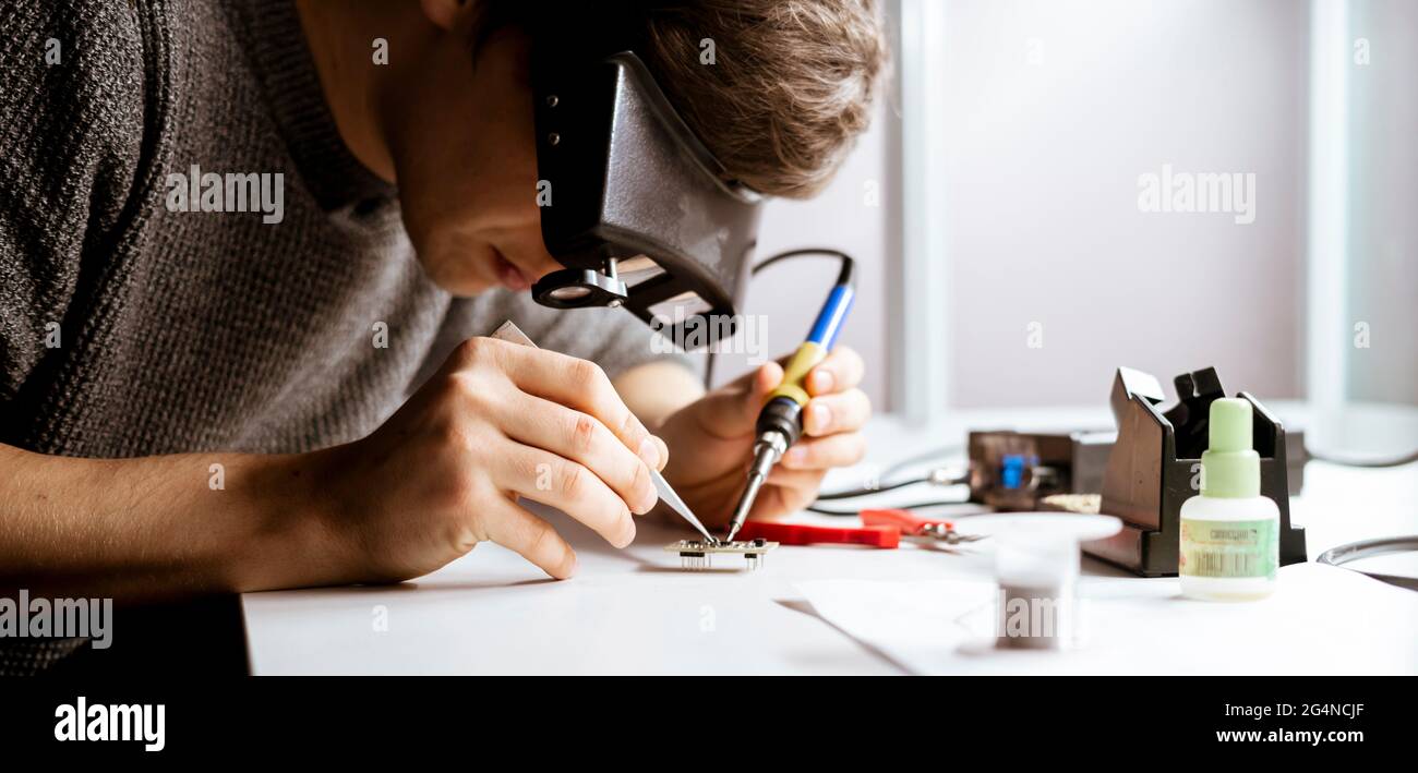 close up cropped shot of the engineer soldering electric components ...
