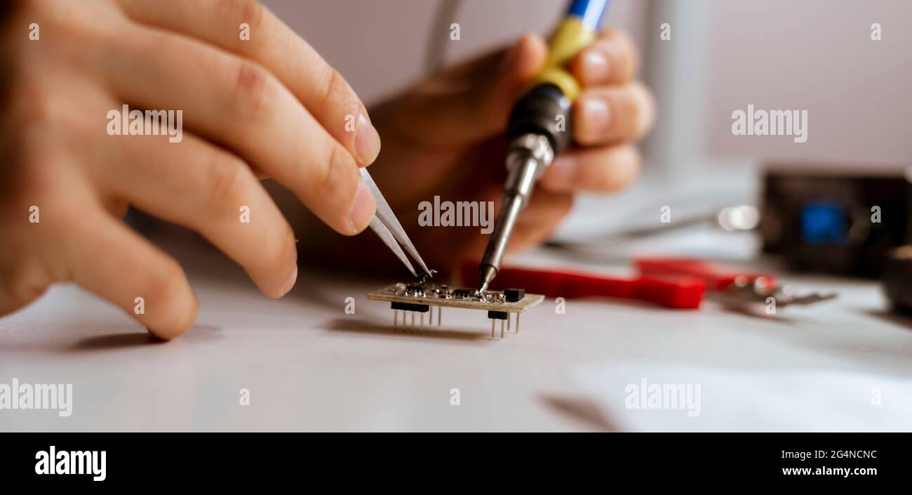 close up cropped shot of the engineer soldering electric components ...