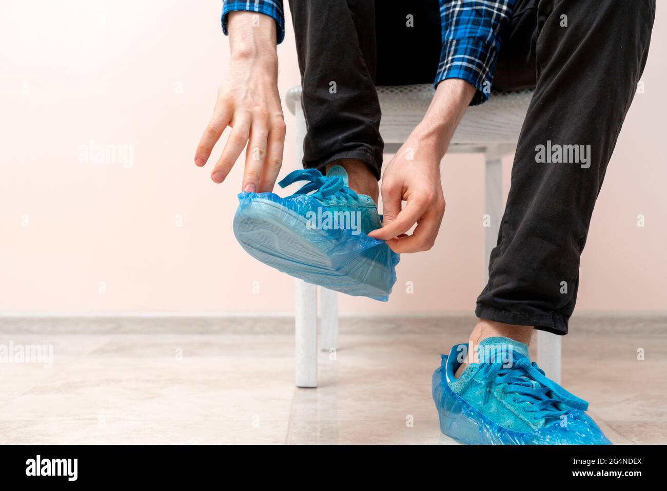 person's hands put on the blue shoe covers on the dirty sneakers in the ...