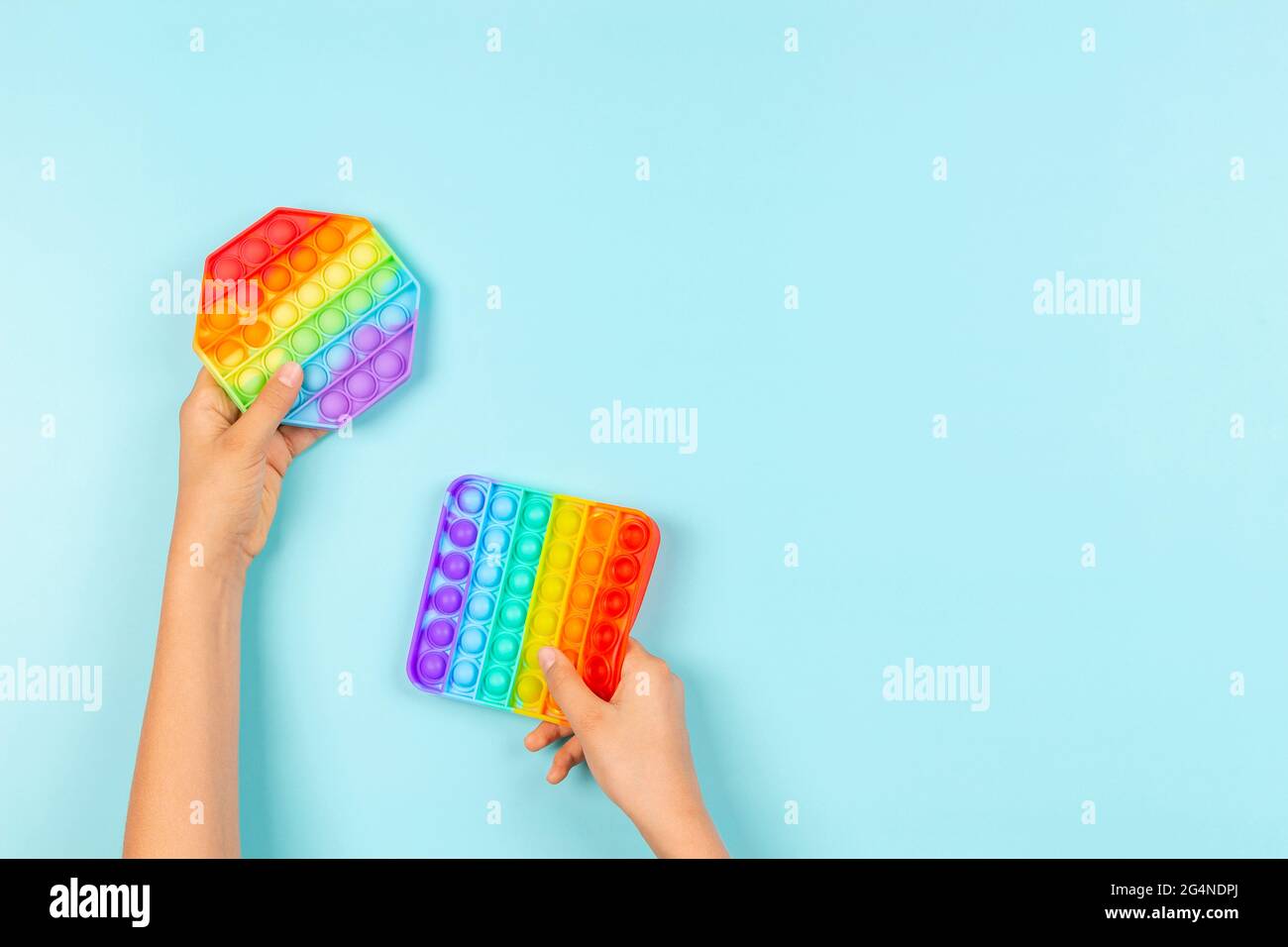 Kids hands holding colorful pop it fidget toys on blue background. Push ...
