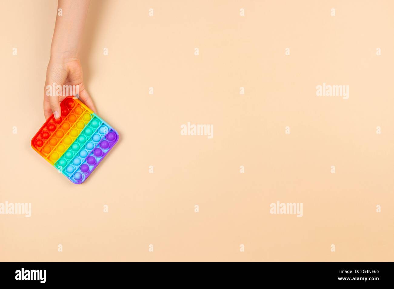 Kid hand holding pop it fidget toy on pastel background. Push pop-it ...
