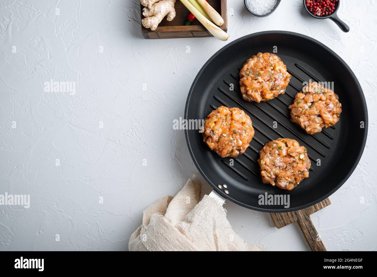 Raw fish patties with salmon fillet and lemongrass, on white textured ...