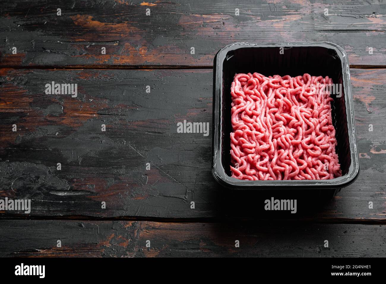 Fresh minced meat in plastic box packaging tray set, on old dark wooden ...