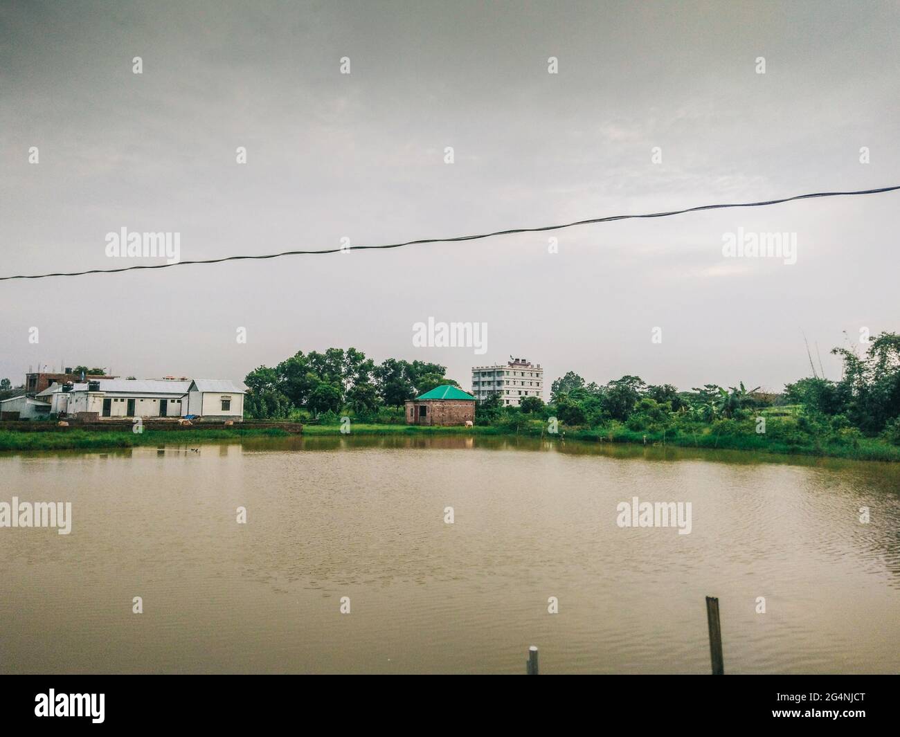 Yellow river with coastline buildings and greenery under cloudy sky ...