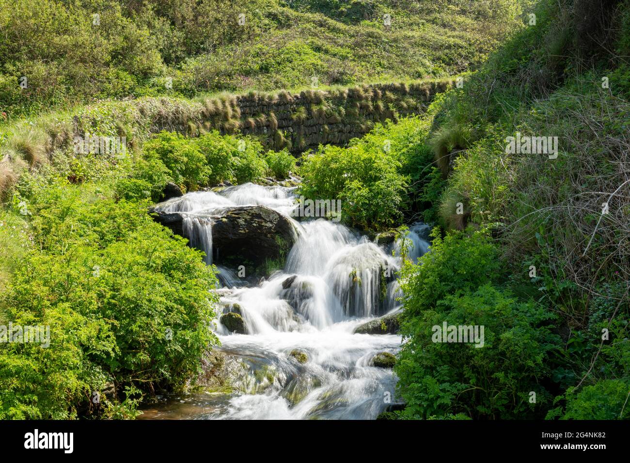 Long exposure of a waterfall flowing onto Lee Abbey Beach in Devon ...