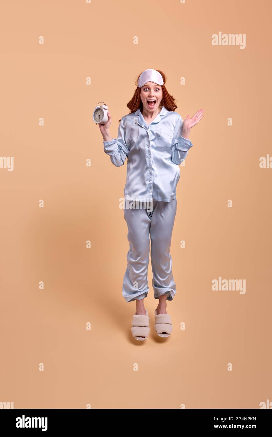Emotional redhead woman isolated on beige background in pajamas ...