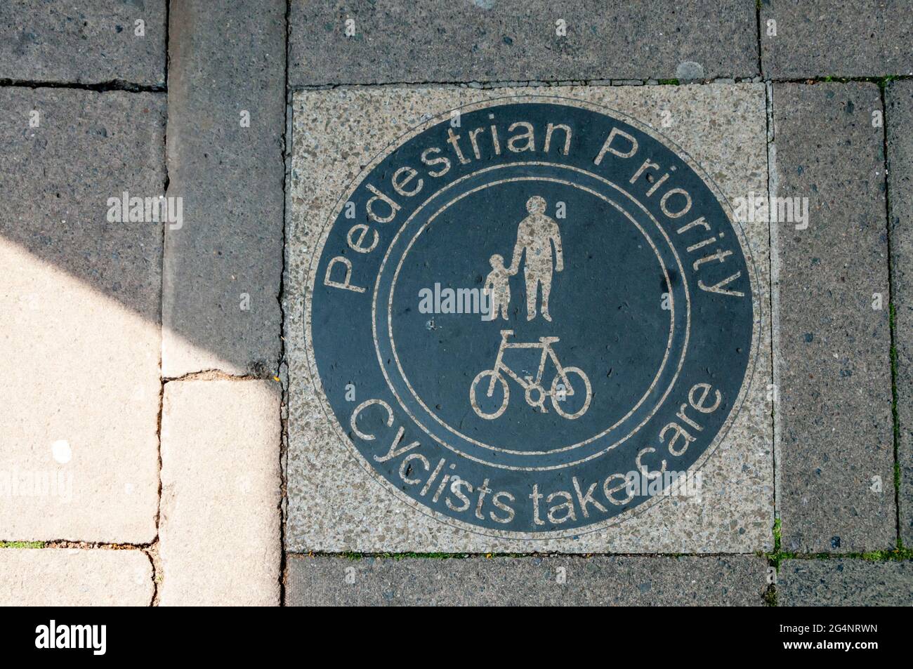A pavement sign reads Pedestrian Priority Cyclists take care, on shared ...