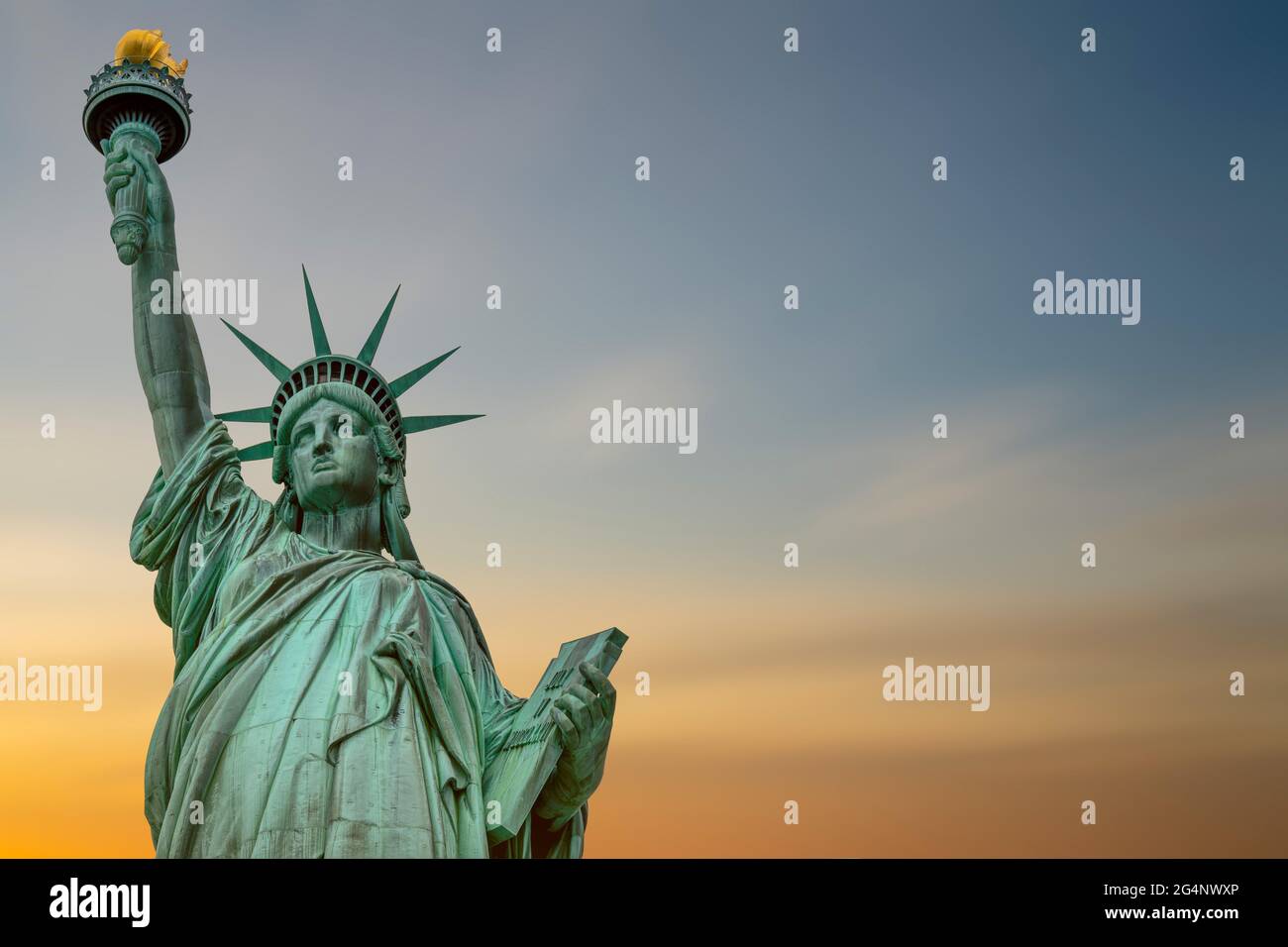 The Statue of Liberty isolated against a warm sky with negative space ...