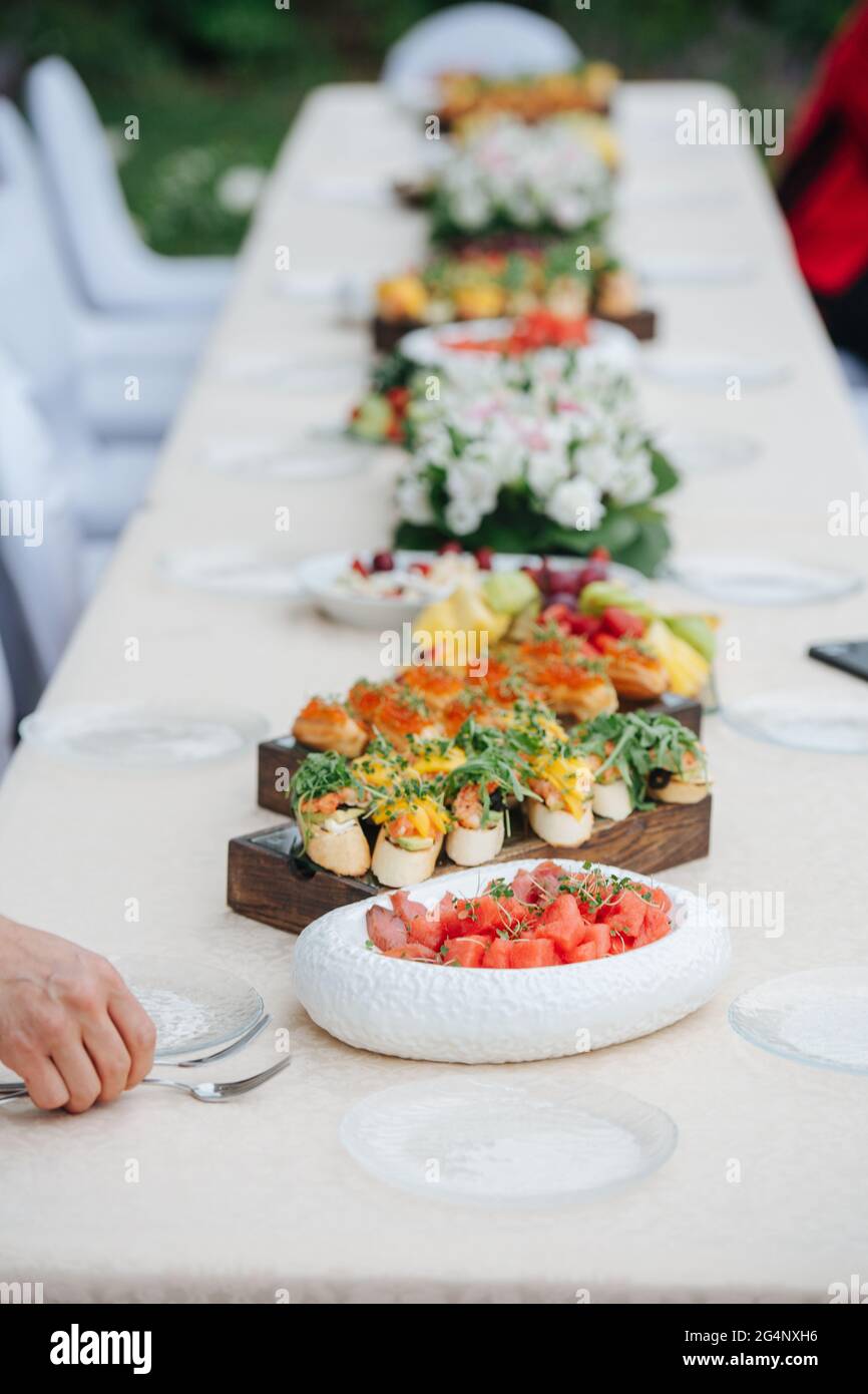 Long and narrow dining table outdoors, abundant in the food. Dishes ...
