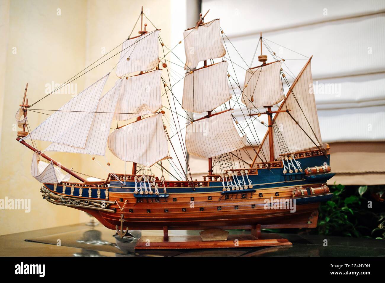Wooden old sail ship model on a stand on a glass table. It has three ...