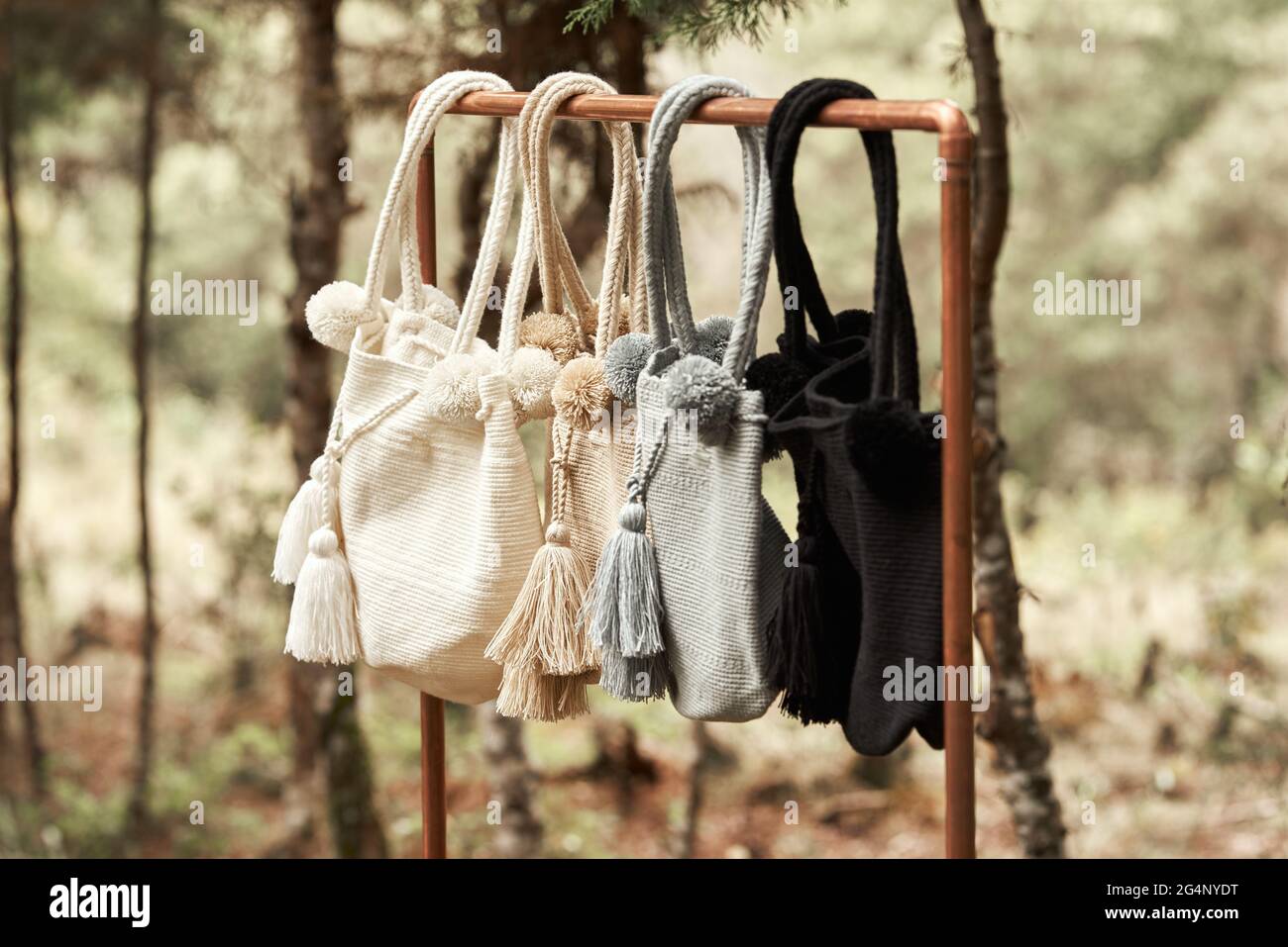 A closeup shot of hanging knit bags on a rack in a park Stock Photo - Alamy