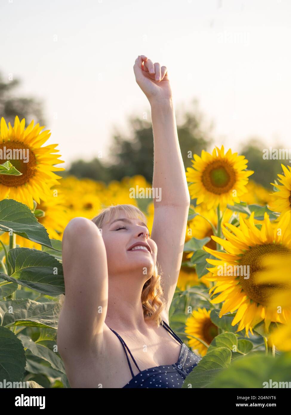 Joyful lady with eyes closed is enjoying a vacation in the sunflower ...