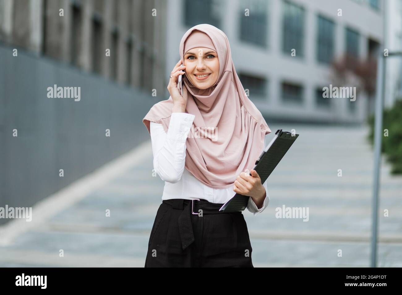 Muslim business woman in formal clothes and hijab standing on street ...