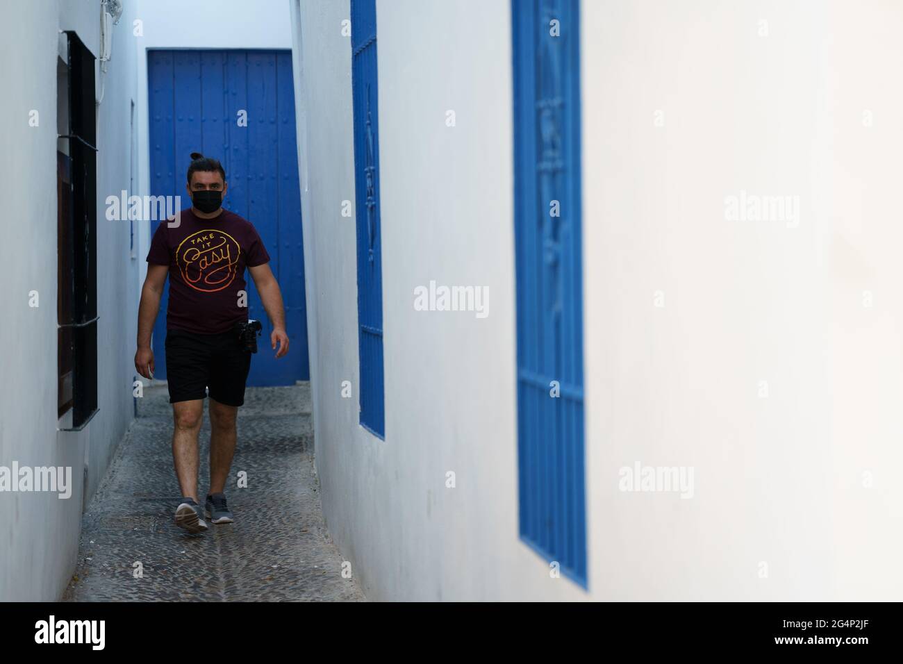 A man walking in the narrow streets through the white buildings Stock ...